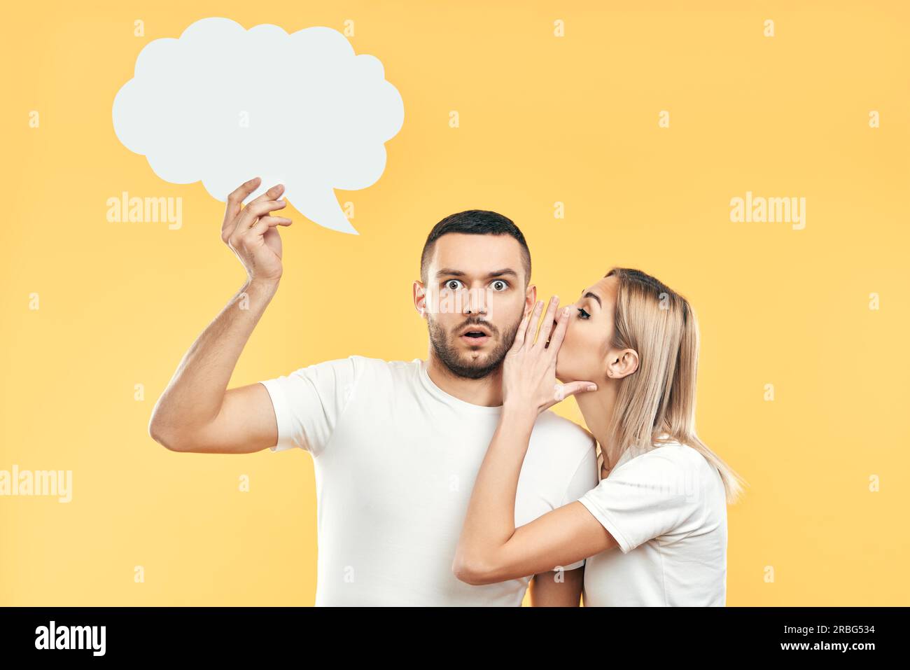 Young woman whispering secrets to man with paper thought bubble over ...