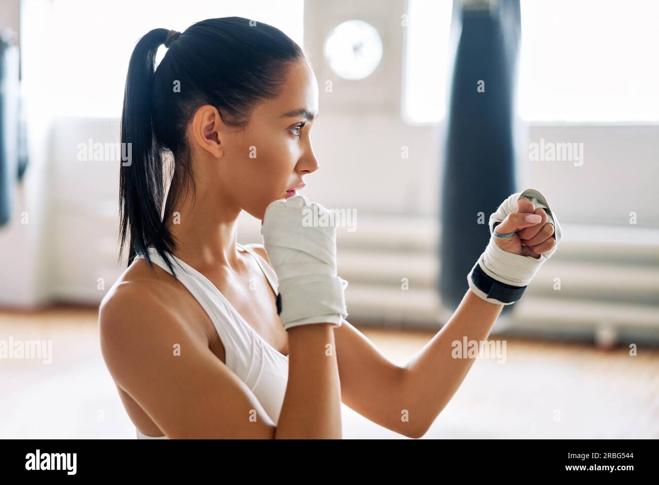 Young boxer woman posing in combat stance in gym. Sporty female ready ...