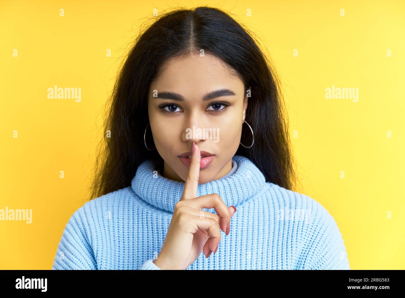 Pretty black woman keeps finger on lips, making hush gesture on yellow ...