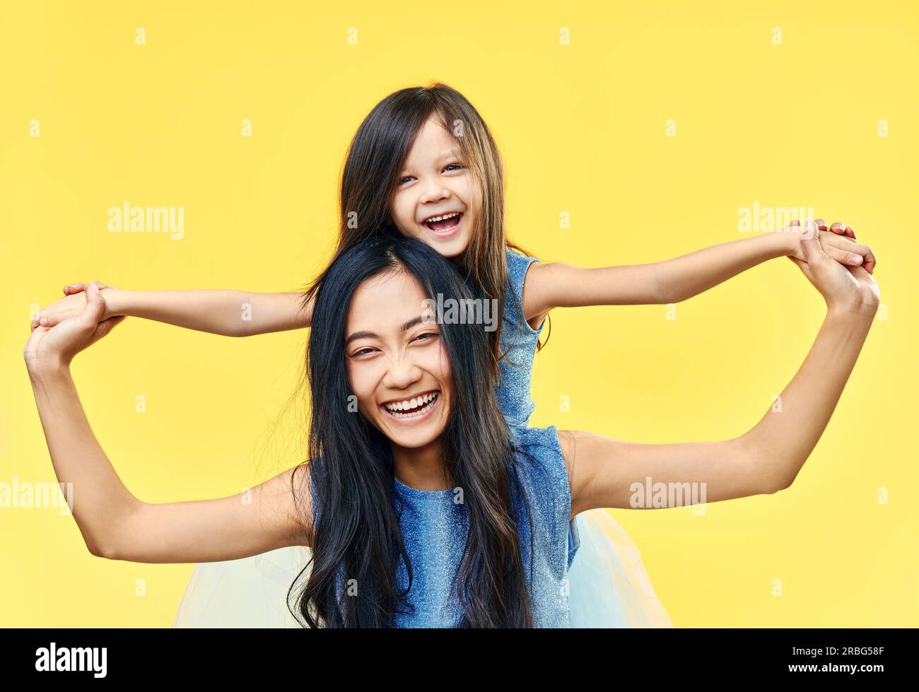 Happy mother and her child daughter have fun together on yellow ...