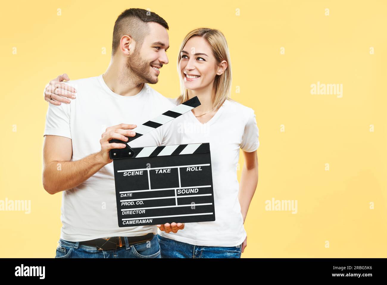 Young happy couple with cinema clapper board over yellow background ...