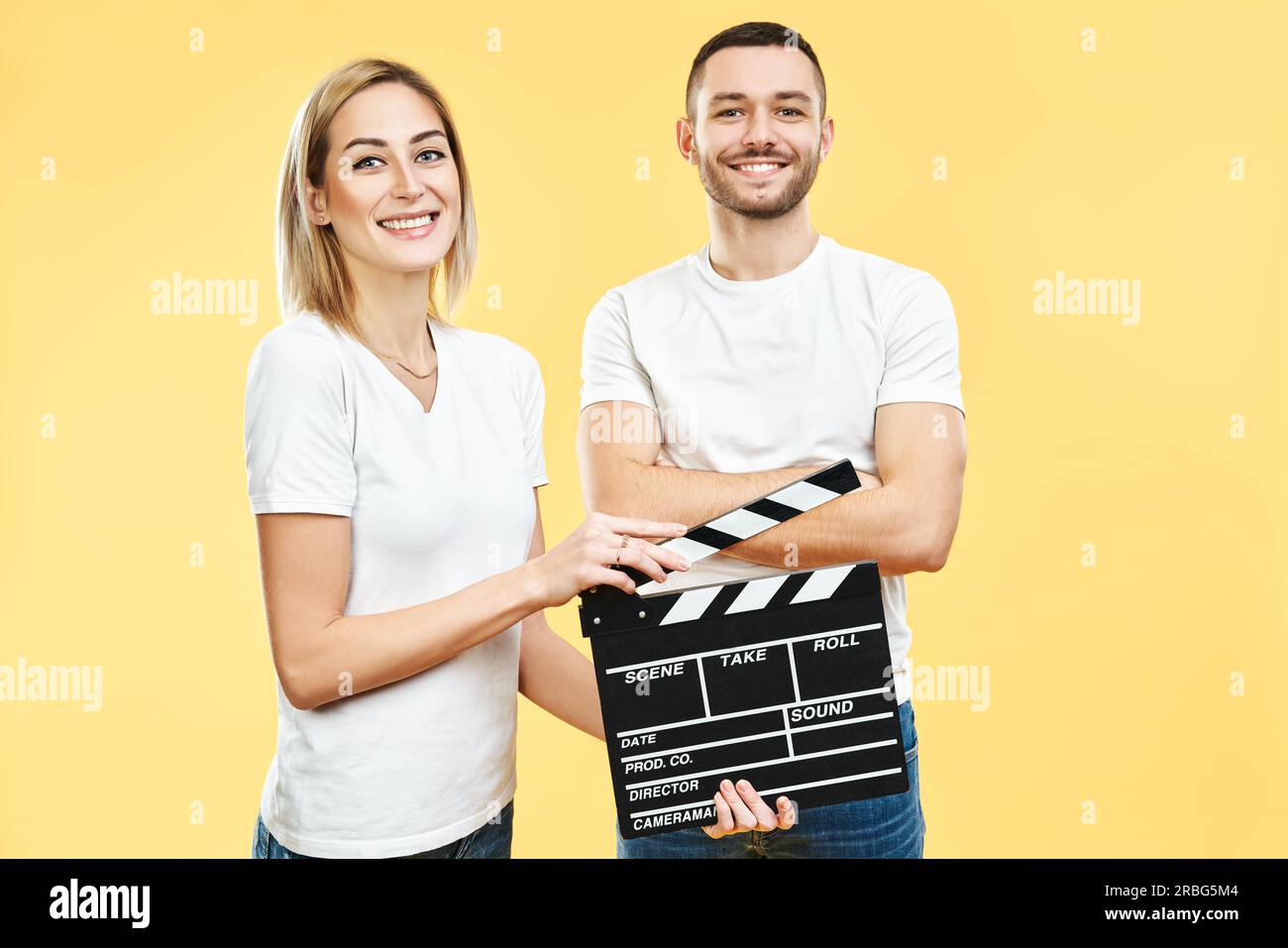 Young happy couple with cinema clapper board over yellow background ...