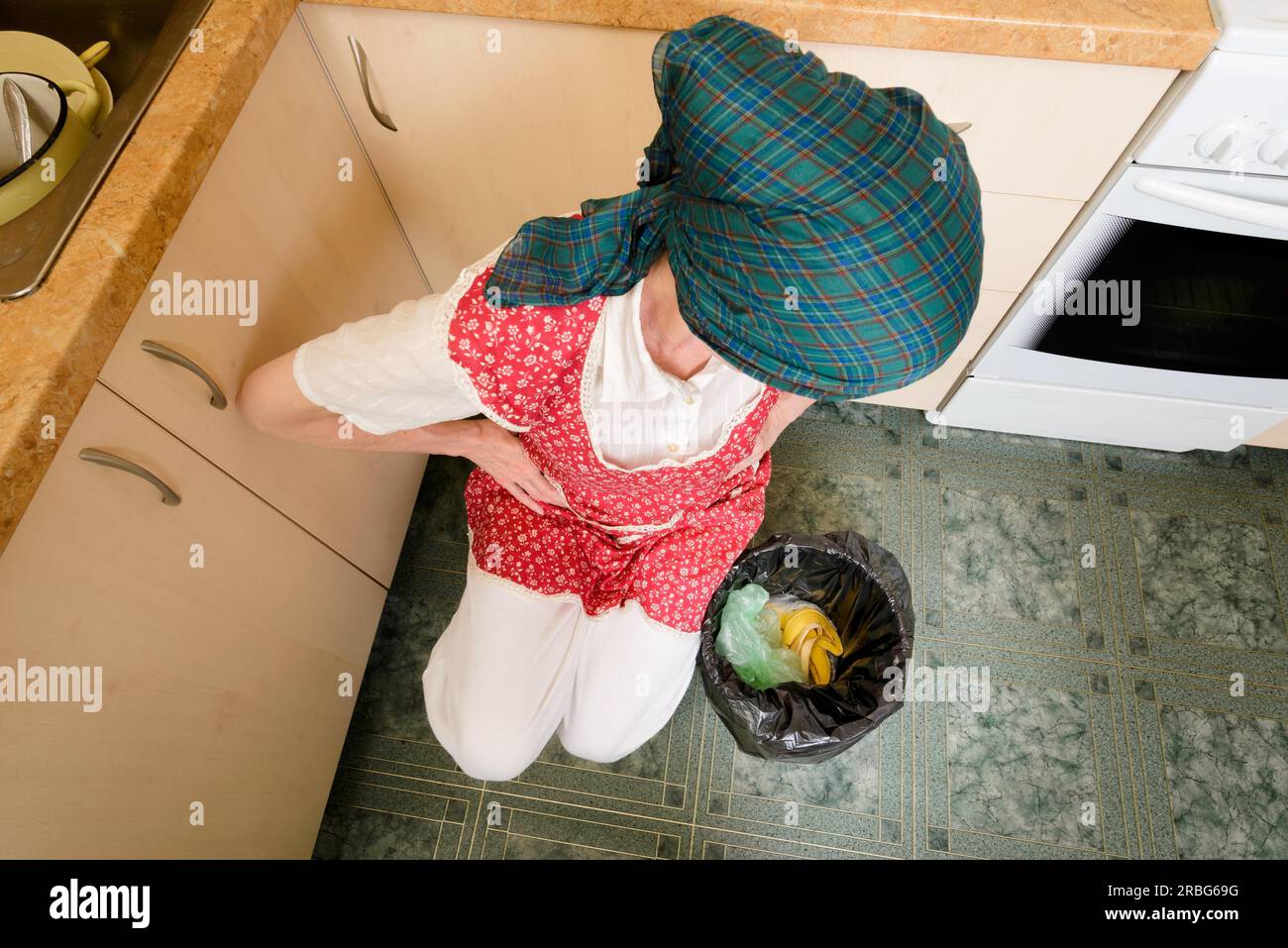 A woman, with a scarf on the head and a red apron, is looking inside a ...