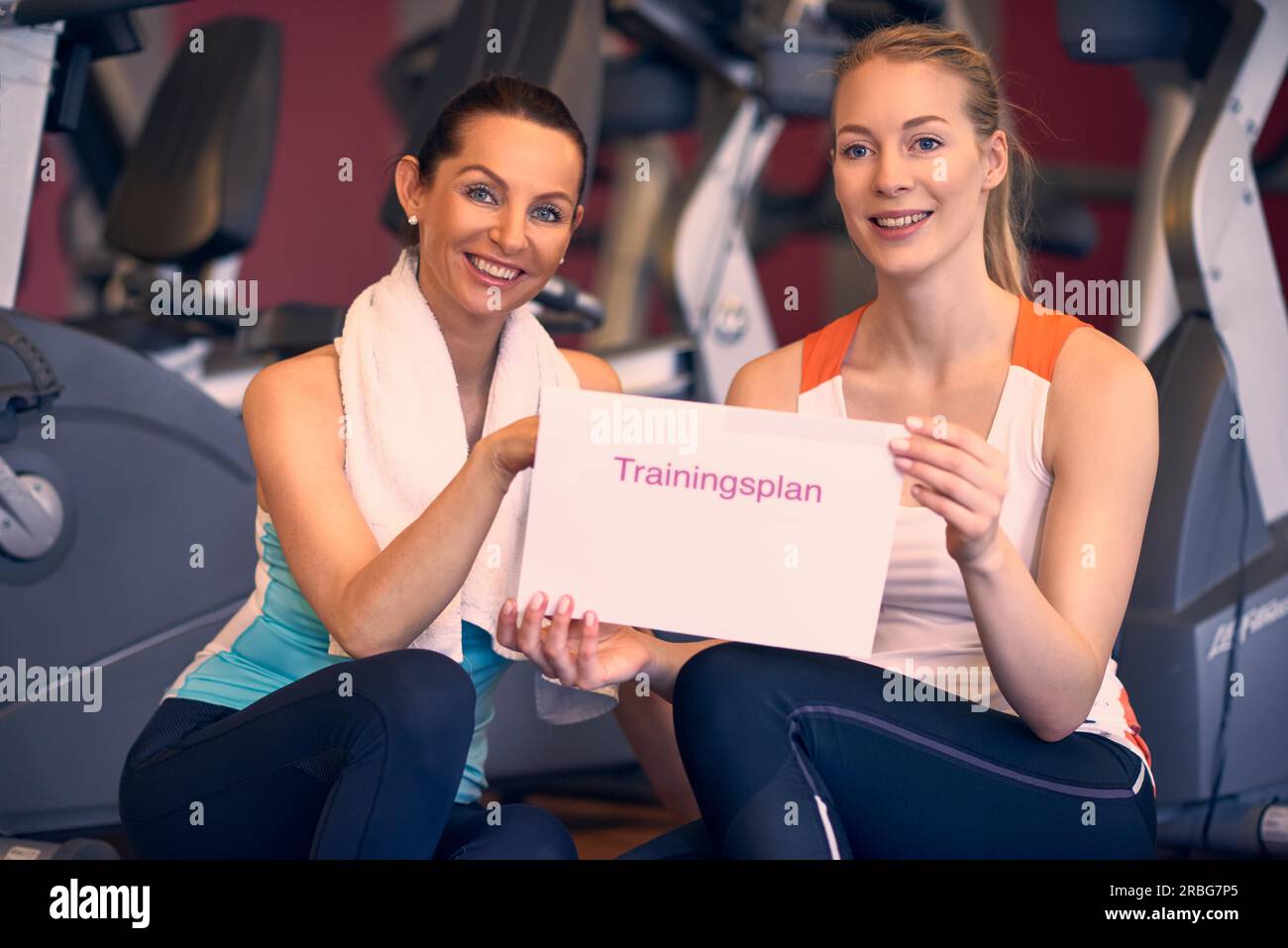 Attractive fit young female athlete with her personal trainer holding ...