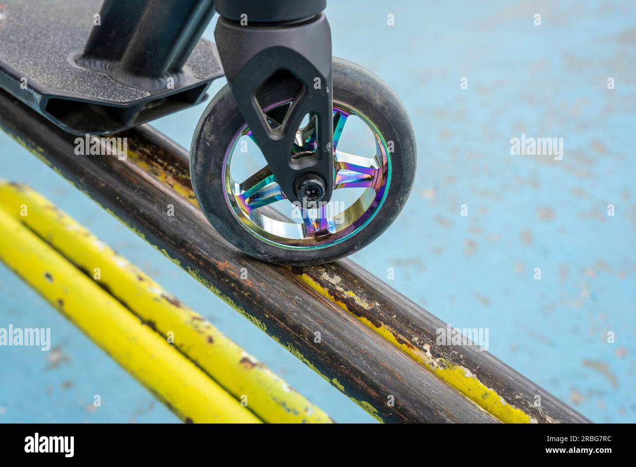 Stunt scooter on the yellow iron tube ramp of the skate park. Jumps and ...