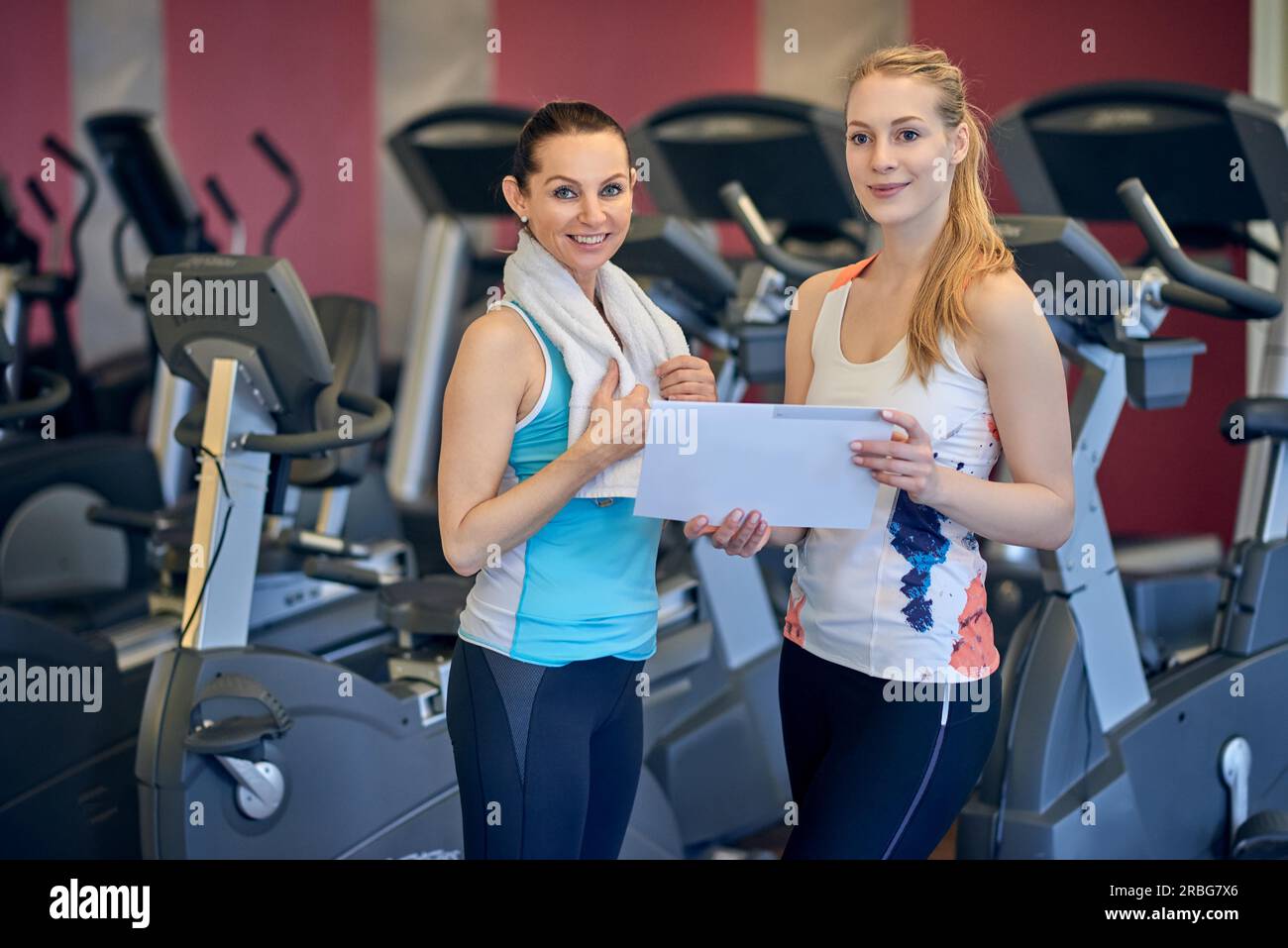 Attractive fit young female athlete with her personal trainer holding ...