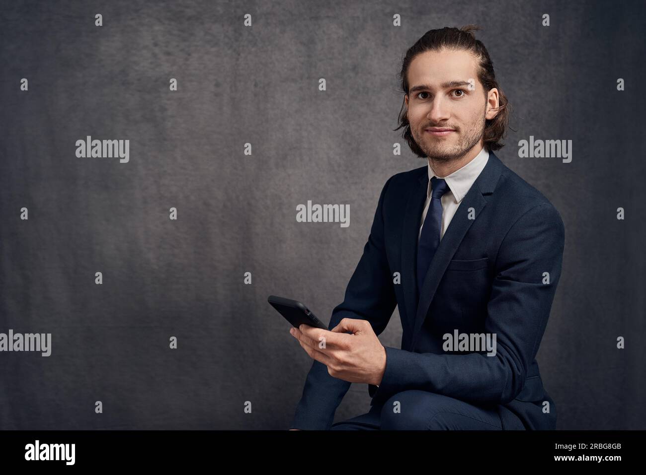 Handsome young man with long hair, wearing stylish suit and blue tie ...
