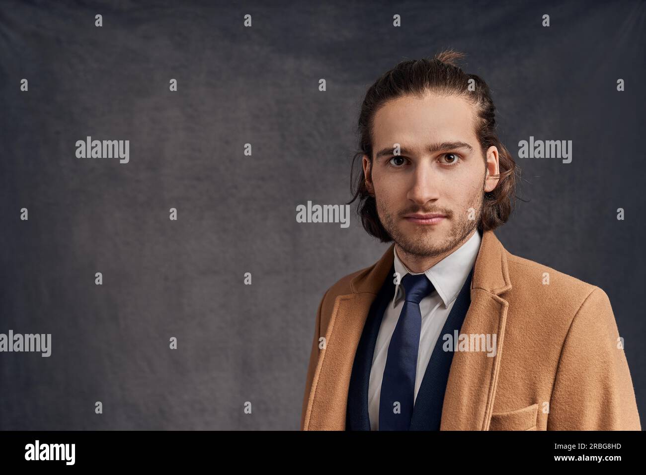 Portrait of a stylish young handsome long-haired unshaven man in light ...