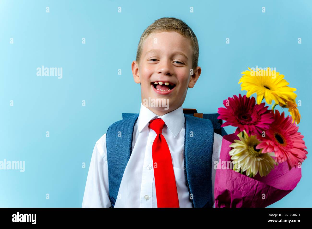 a happy funny first grader in a white shirt with a backpack holds a ...