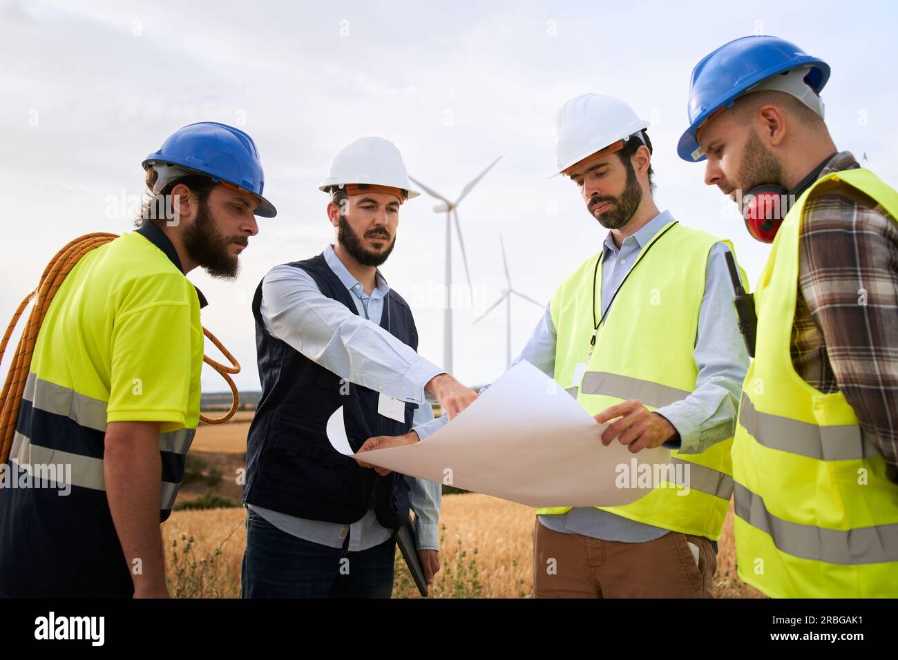 Group of caucasian engineers male checking wind turbines using plans ...