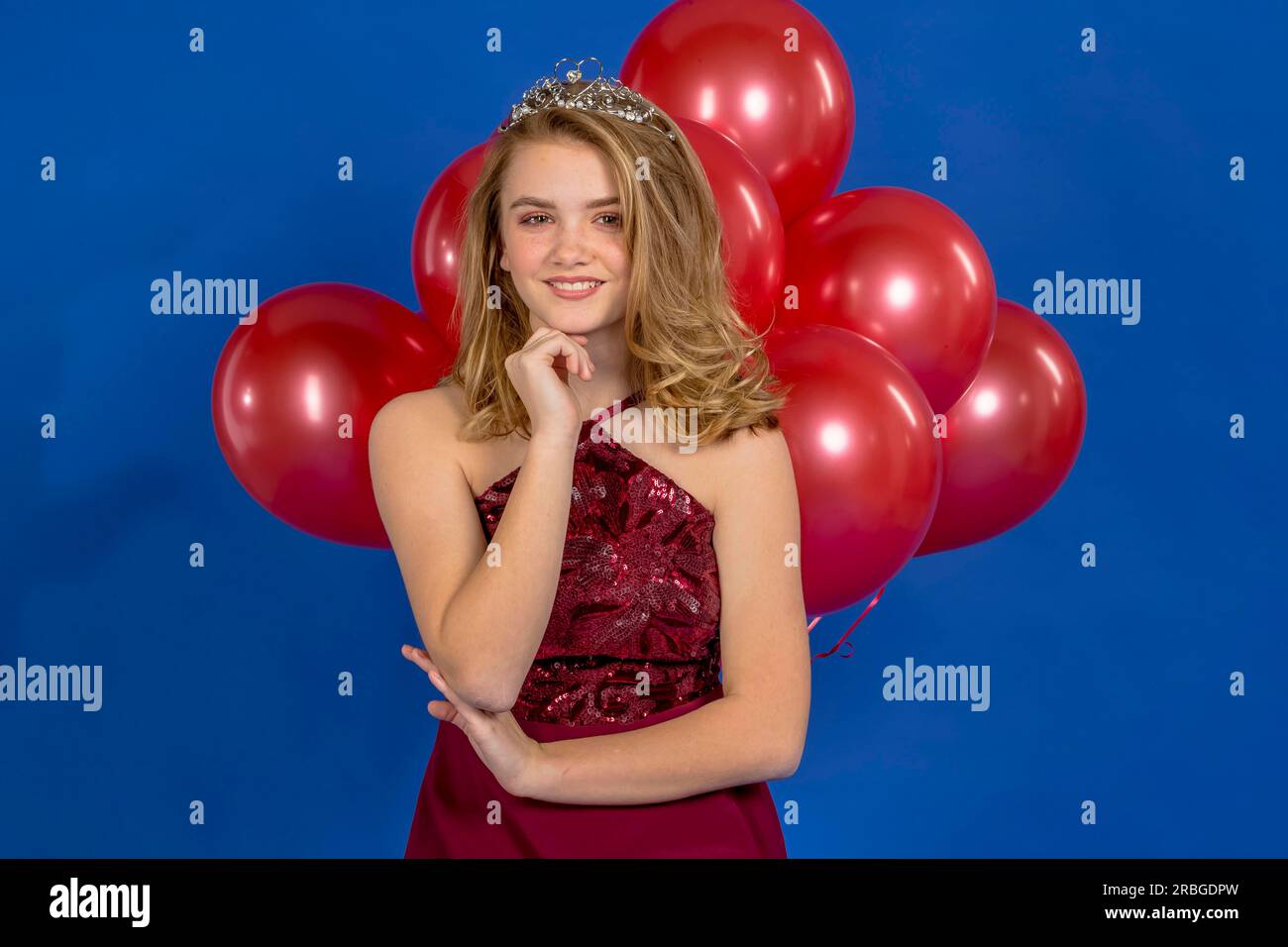 A beautiful blonde teenage model posing in a tiara and red balloons in ...