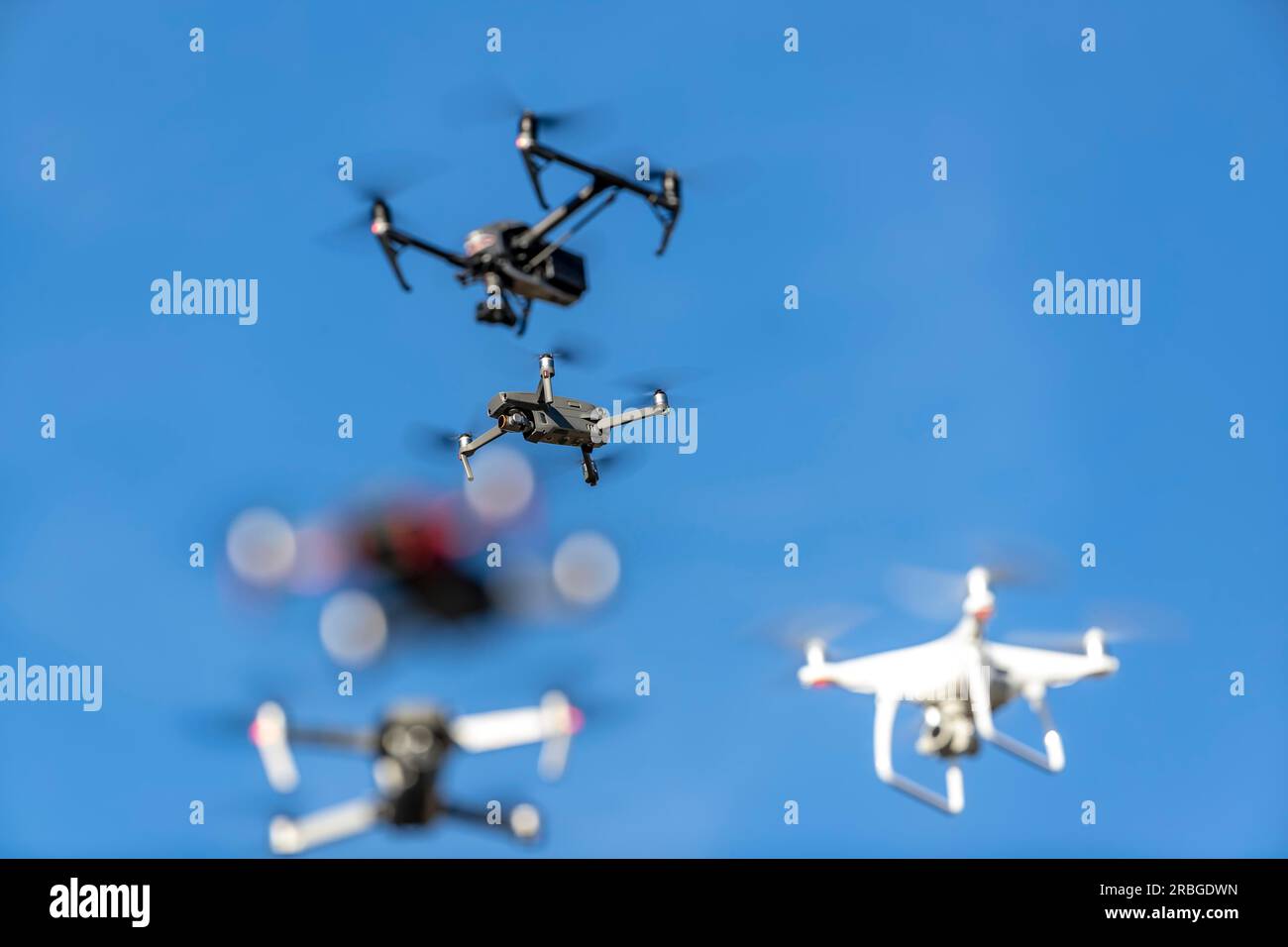 A group of drones fly through the air against a blue sky Stock Photo ...