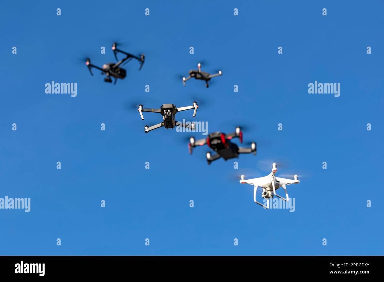 A group of drones fly through the air against a blue sky Stock Photo ...