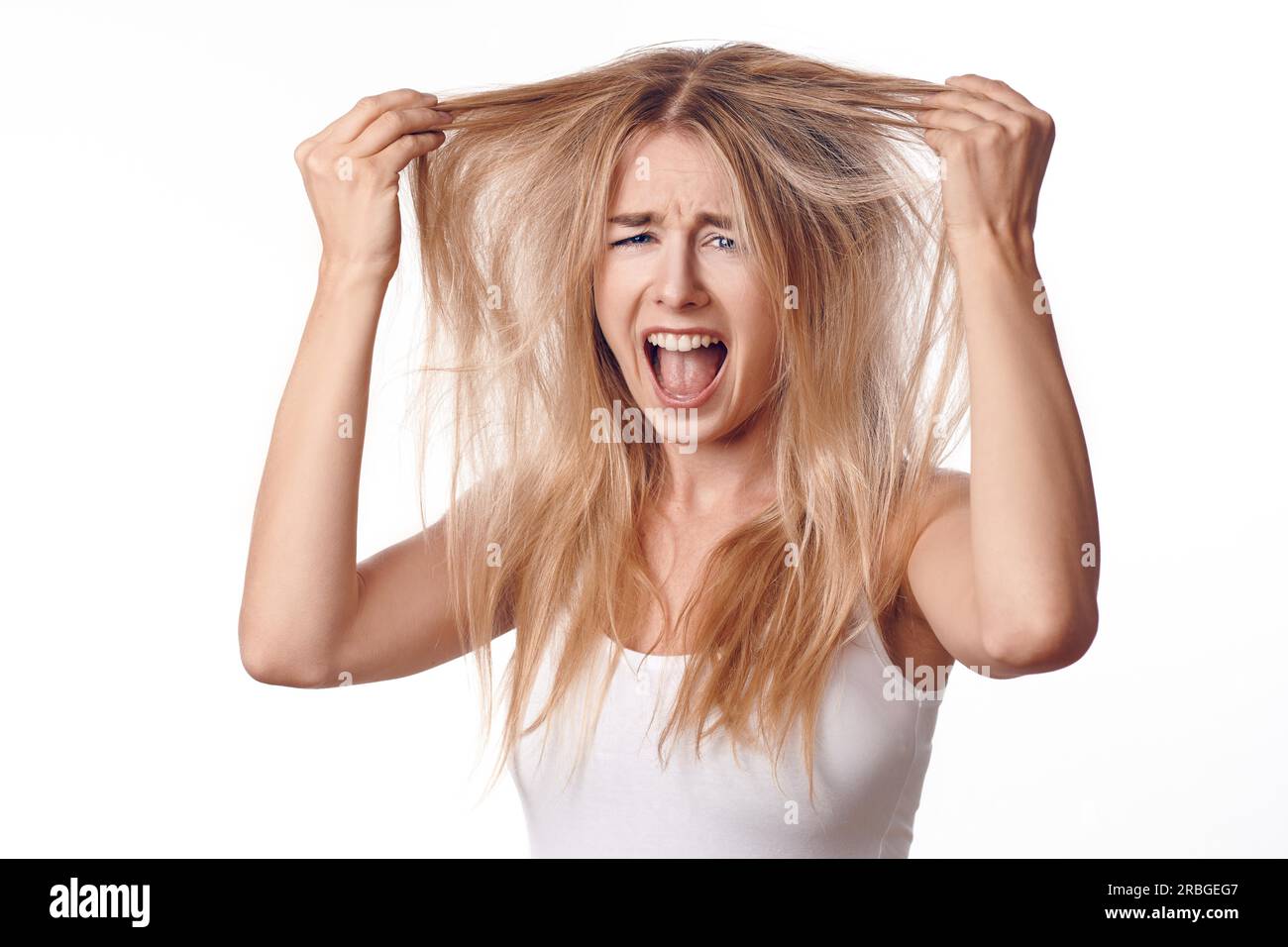 Young blond woman unhappy with her haircut, touching her hair with both ...
