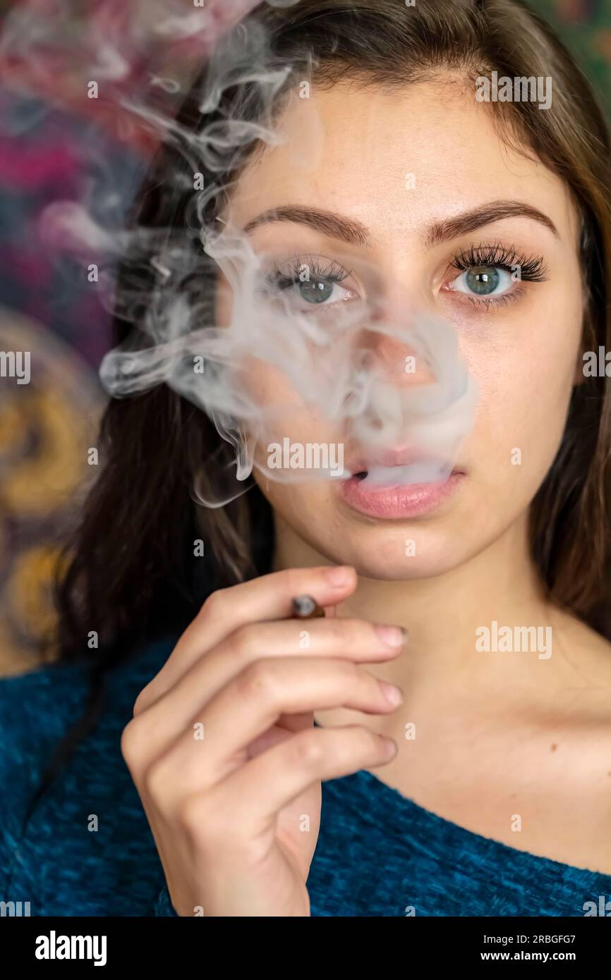 A beautiful brunette model smokes marijuana in the privacy of her own ...