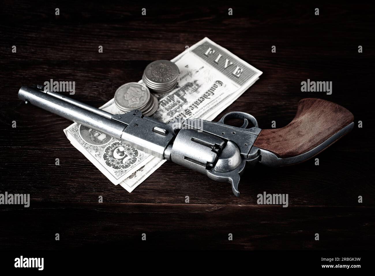 Old west revolver with bill and silver dollars on wooden table Stock ...