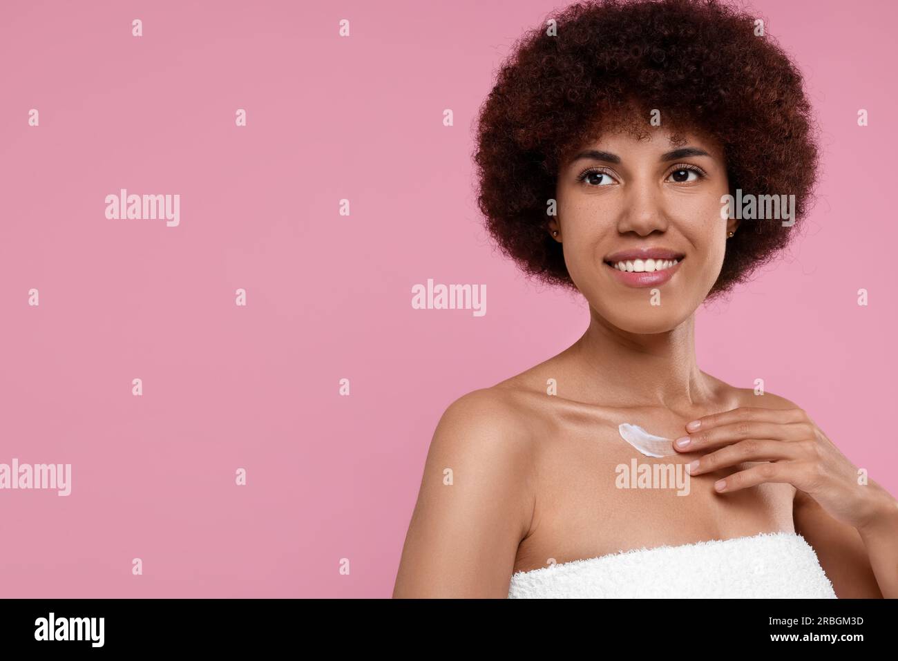 Beautiful young woman applying cream onto body on pink background ...