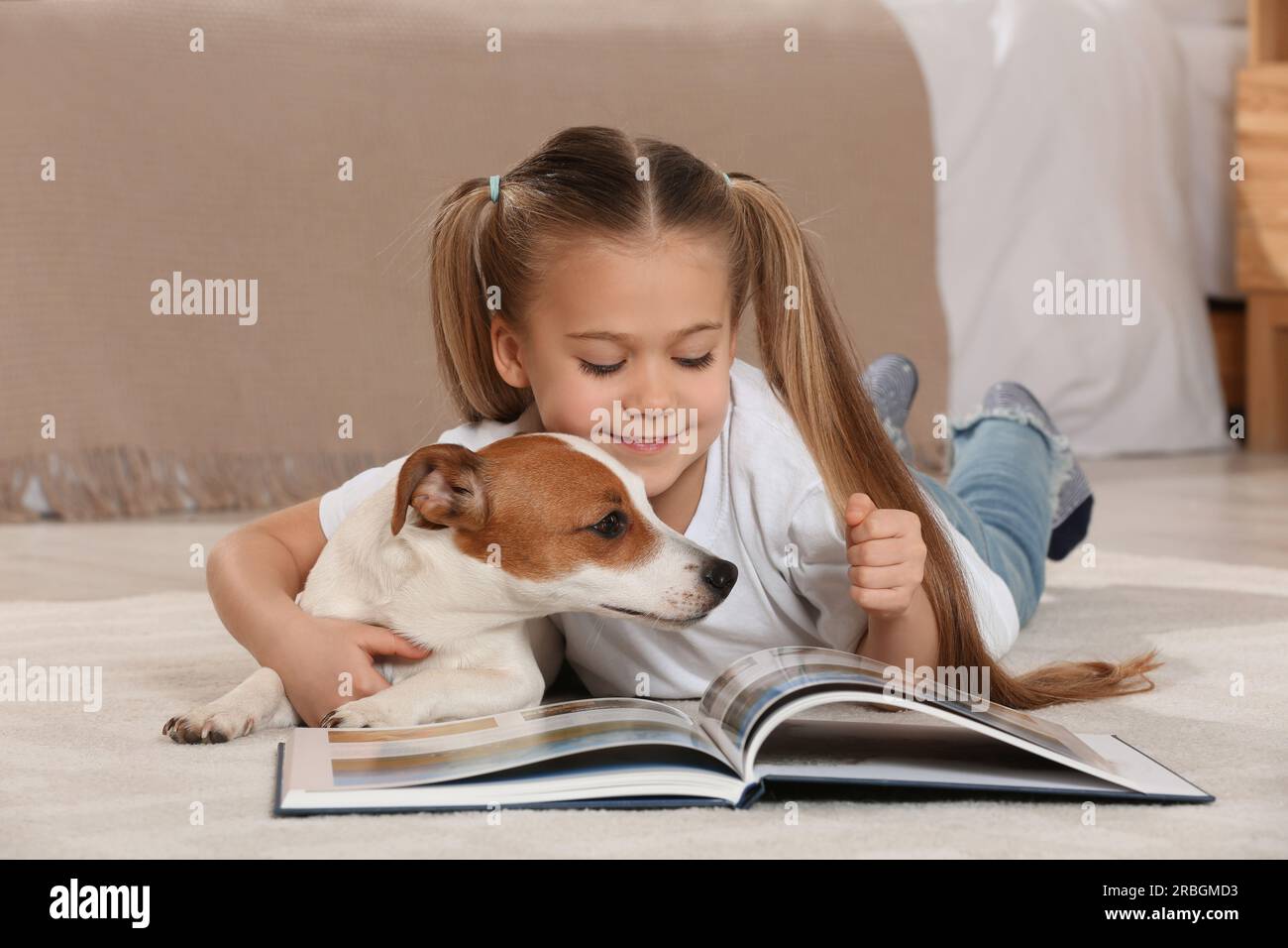 Cute girl reading book on floor with her dog at home. Adorable pet ...