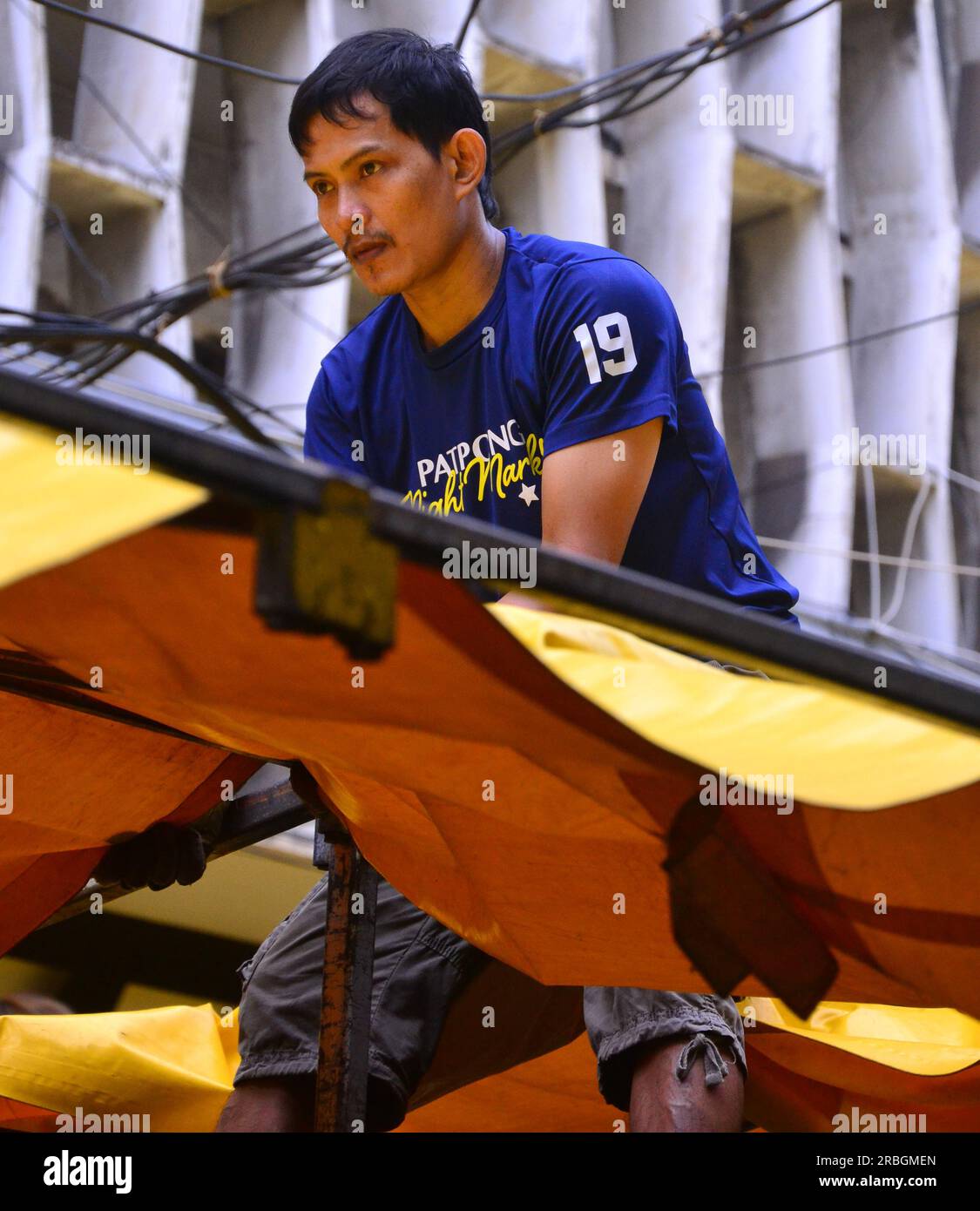 A young man is part of a team of men who assemble the stall structures of Patong Night Market ...