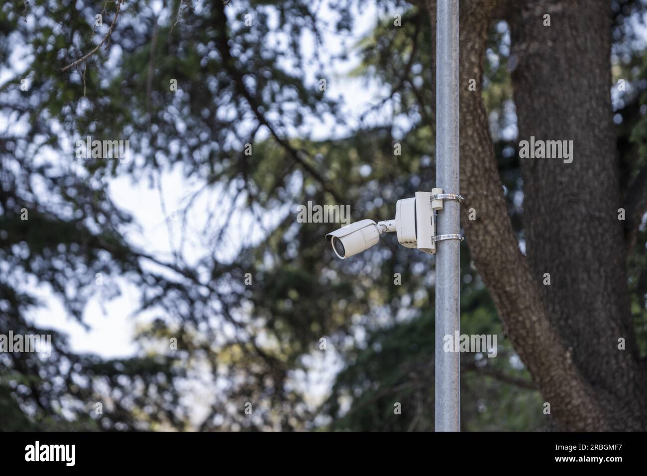A small surveillance camera attached to a thin metal post next to some ...