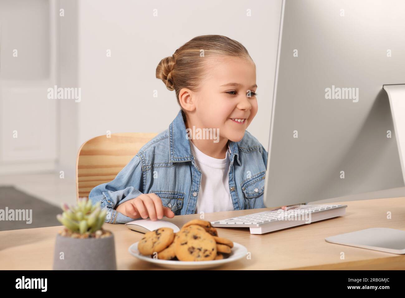 Little girl using computer at table in room. Internet addiction Stock ...