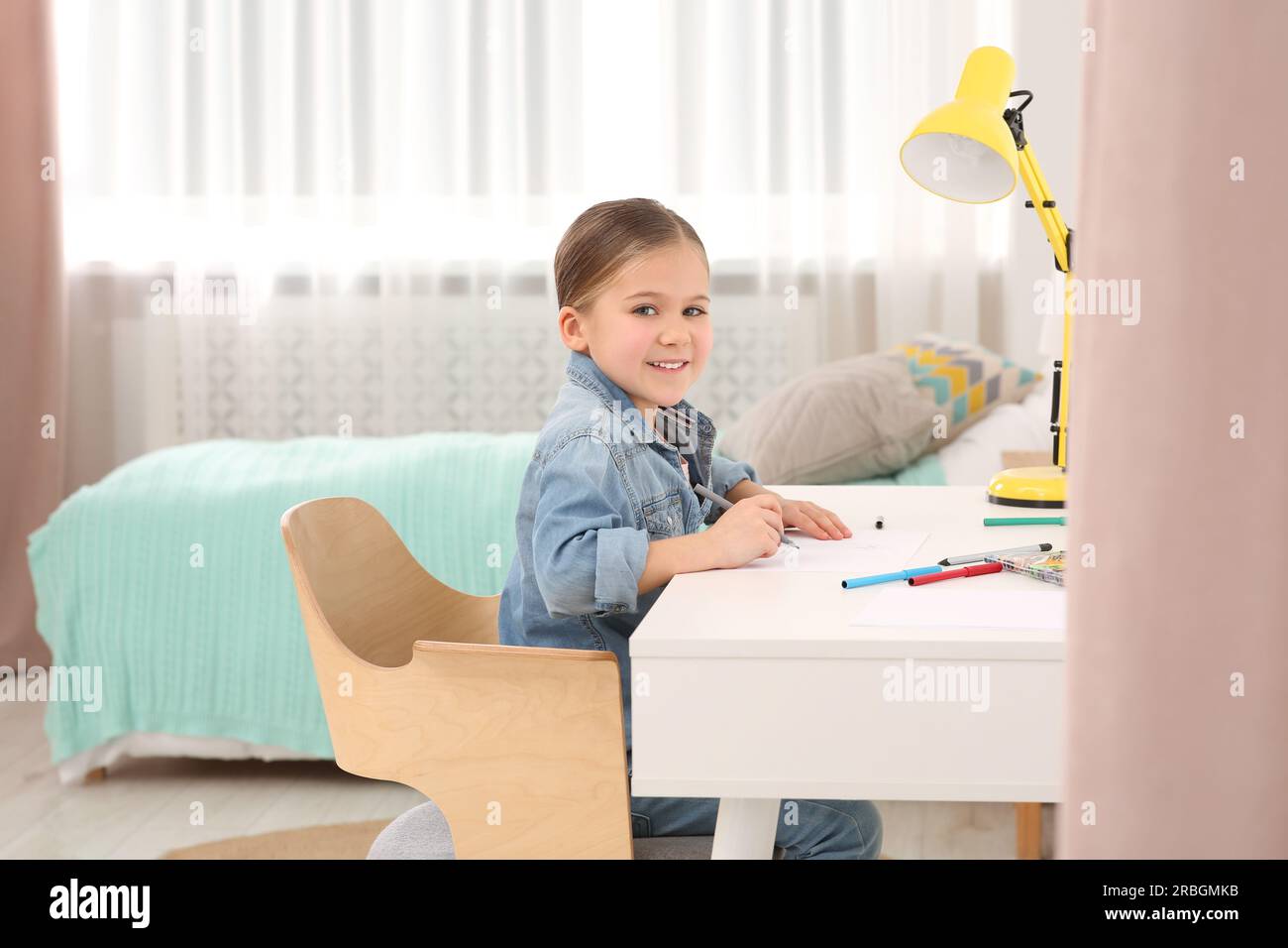 Cute little girl drawing with marker at desk in room. Home workplace ...