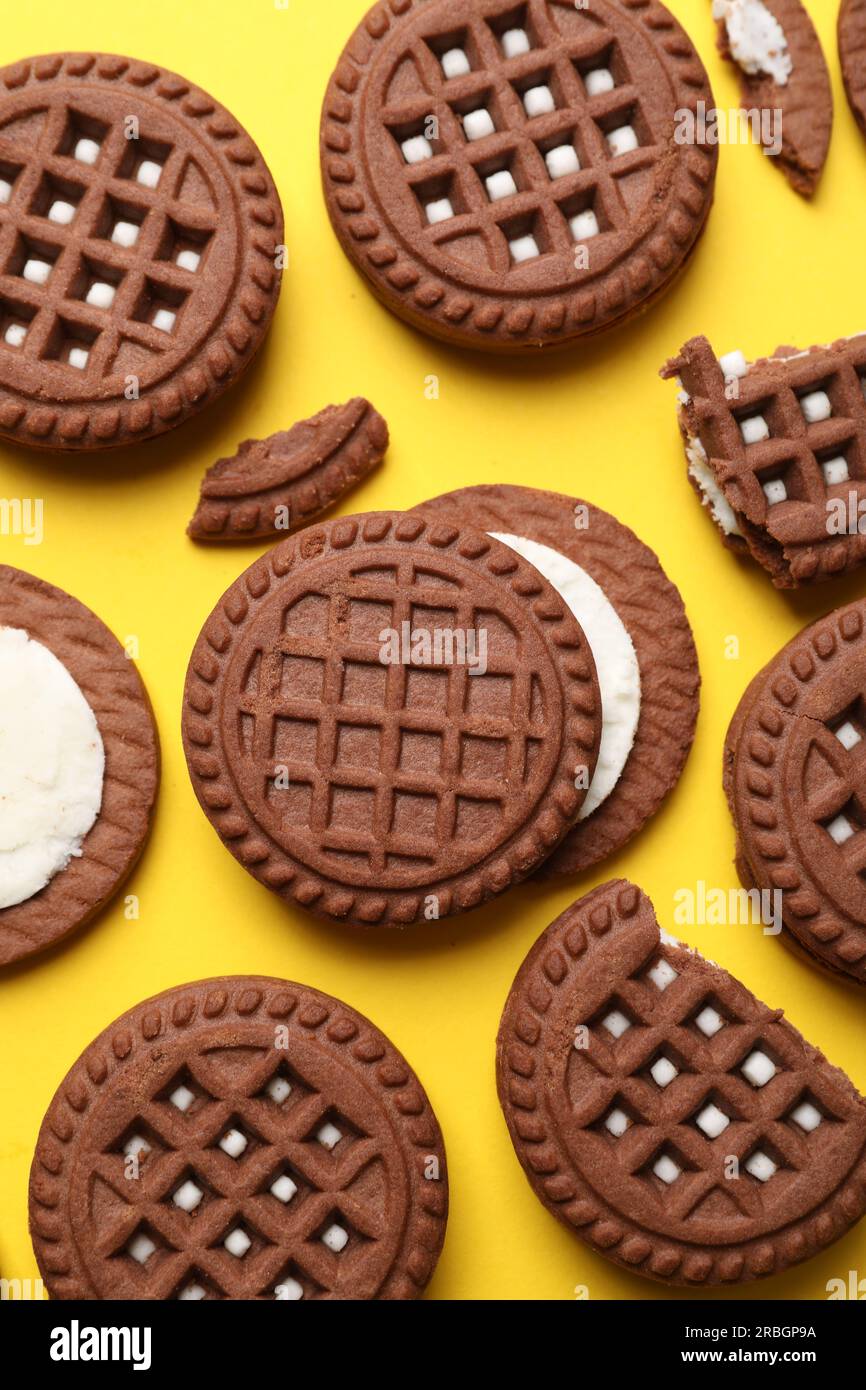 Tasty chocolate sandwich cookies with cream on yellow background, flat ...