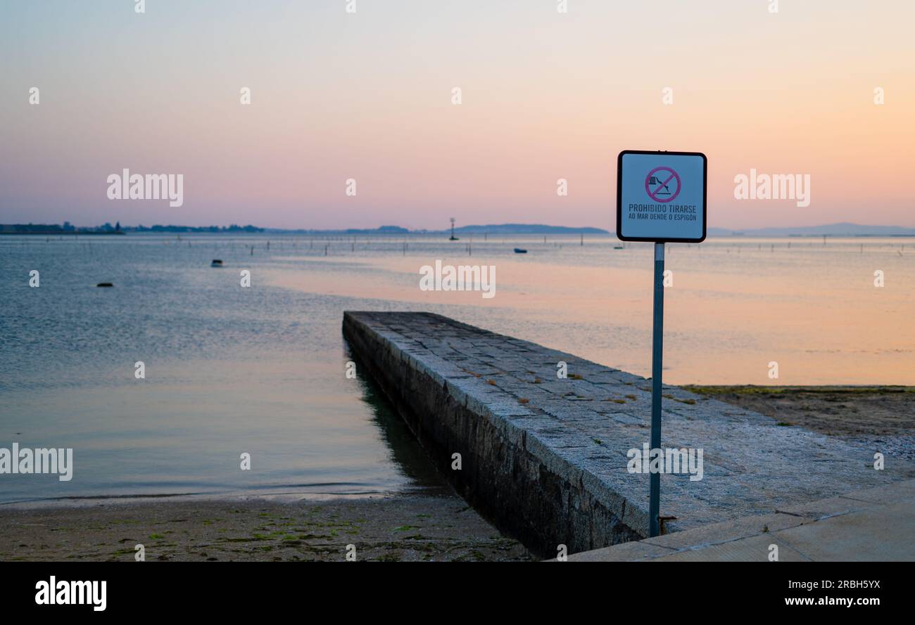 jetty with a sign prohibiting diving into the water on the sunset Stock ...