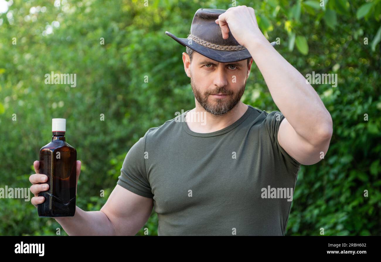 cowboy man hold whisky bottle. cowboy man with whisky outdoor. photo of ...