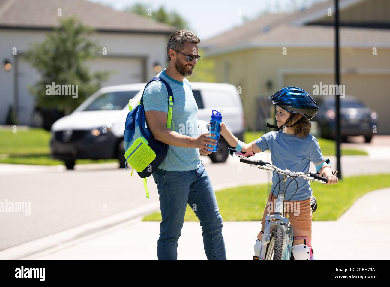 Supportive father guiding son first bike ride. Father and son sharing ...