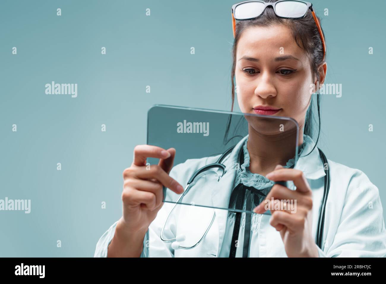 Young woman doctor uses a digital tablet as a diagnostic tool, studying ...