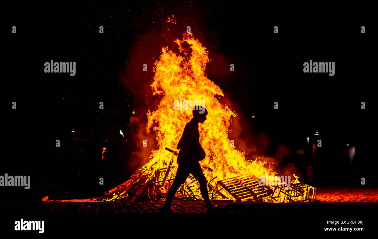 big bonfire on the beach at night with high flames with the silhouette ...