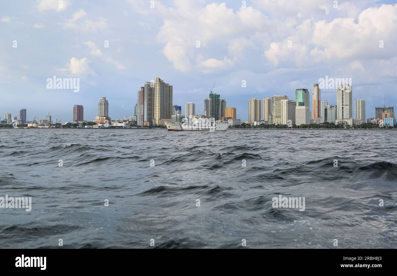 Training ship Admiral Tomas Cloma anchored, Manila Bay skyline see from the sea, Philippines ...