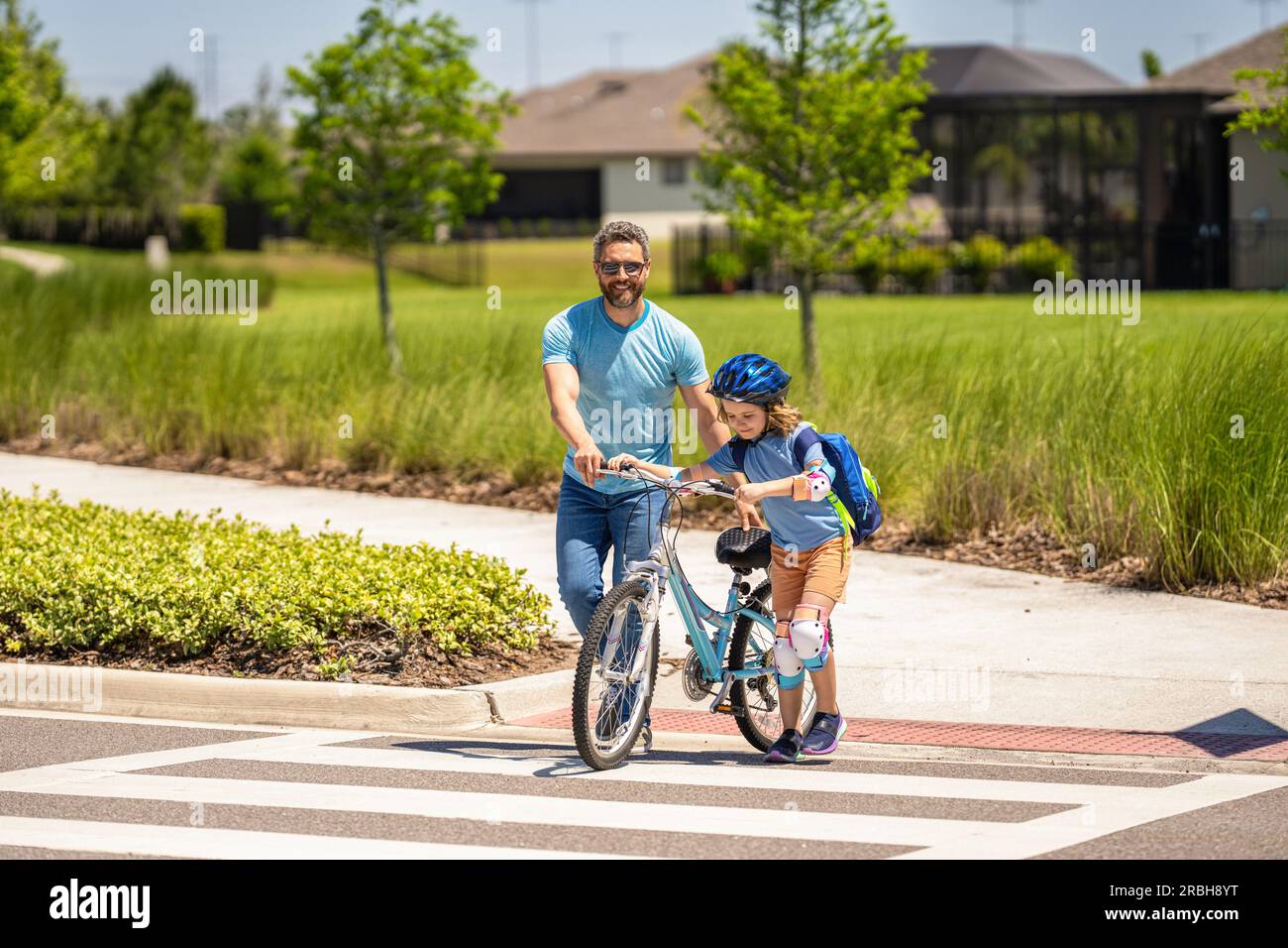 dad guiding his son first bike ride. dad and son enjoying fun bike ...