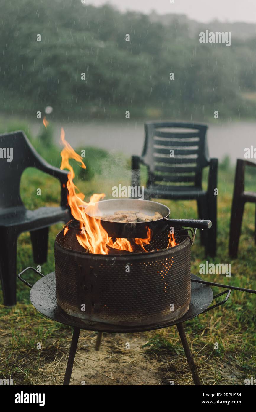 Man cooking fish on fire in nature, camping outdoors Stock Photo - Alamy