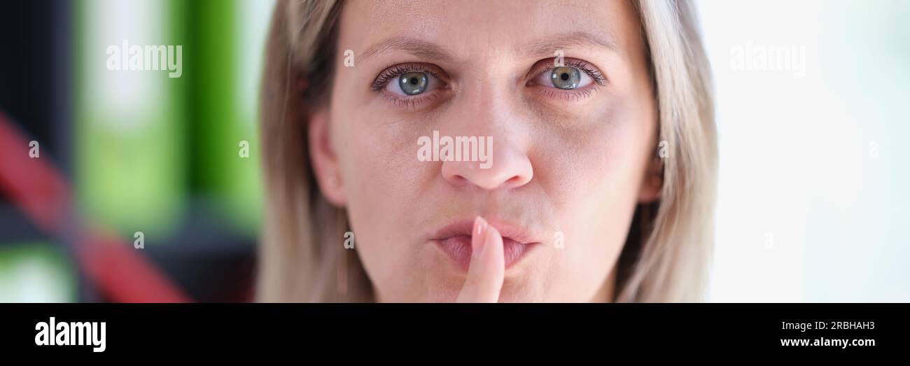 Serious female showing shh sign with finger or to keep silent gesture ...