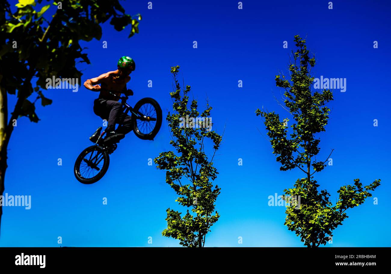 bmx rider jumping high on a blue sky with some trees Stock Photo - Alamy