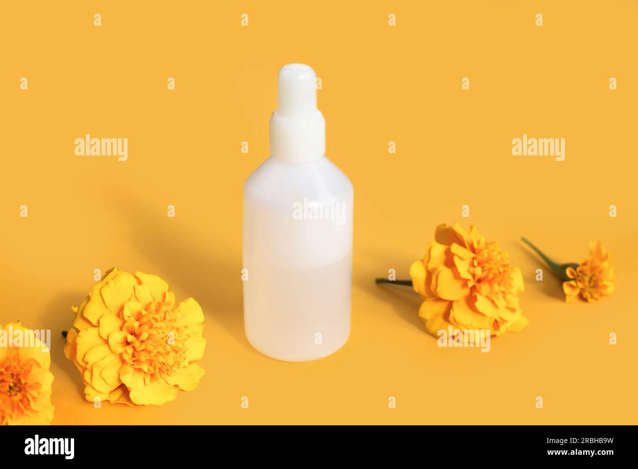 Unbranded white plastic bottle of disinfectant and yellow marigold ...
