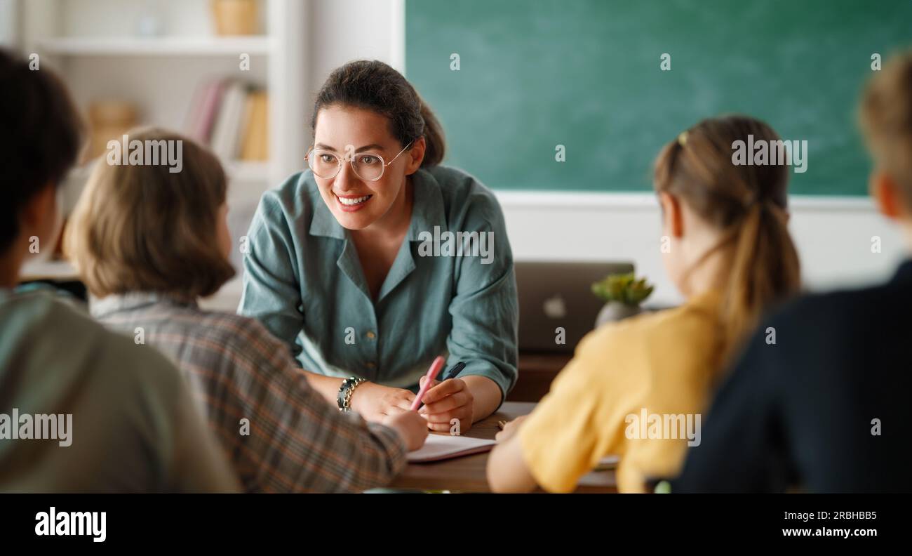 Happy kids and teacher at school. Woman and children are talking in the ...