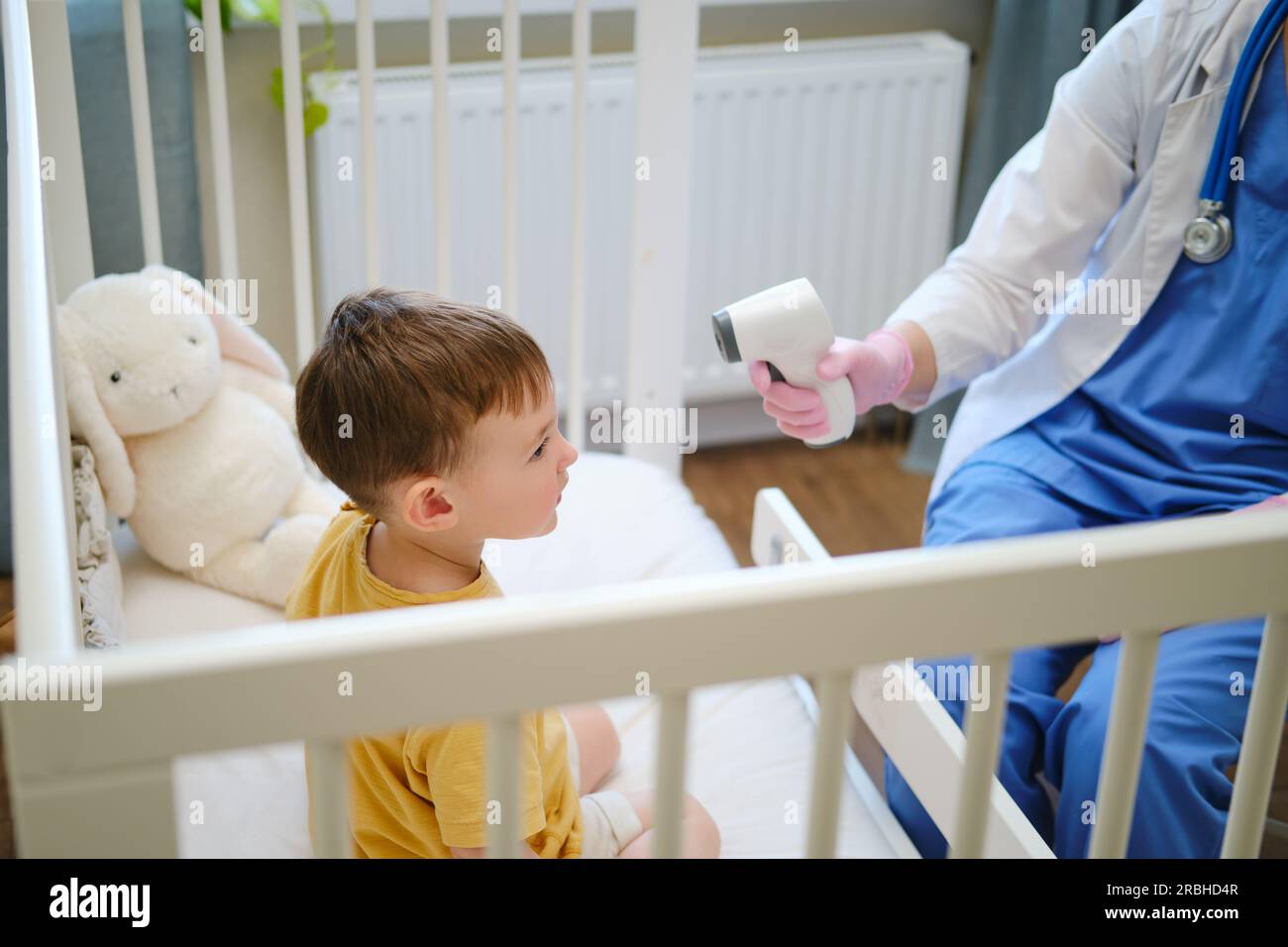 The nurse is checking the toddler's temperature with a contactless ...