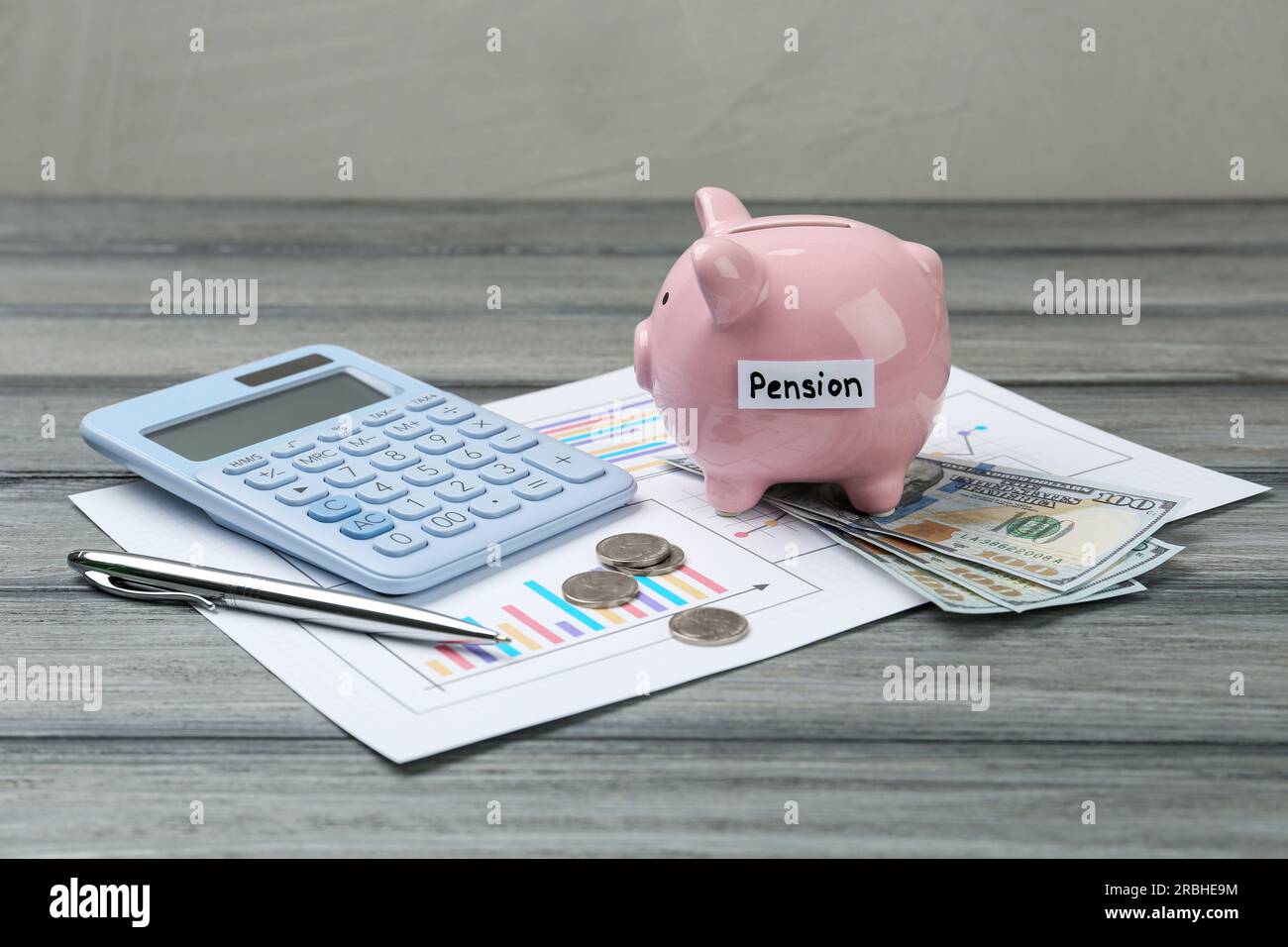 Piggy bank with word Pension, dollar banknotes, coins, pen, calculator ...