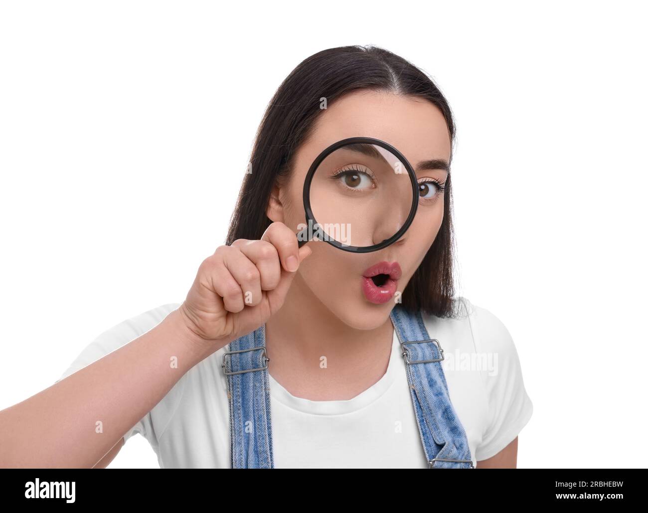 Curious young woman looking through magnifier glass on white background ...