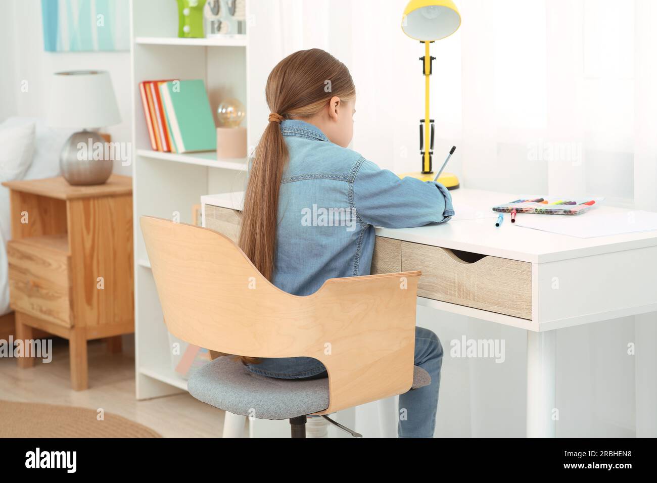 Cute little girl drawing with markers at desk in room. Home workplace ...