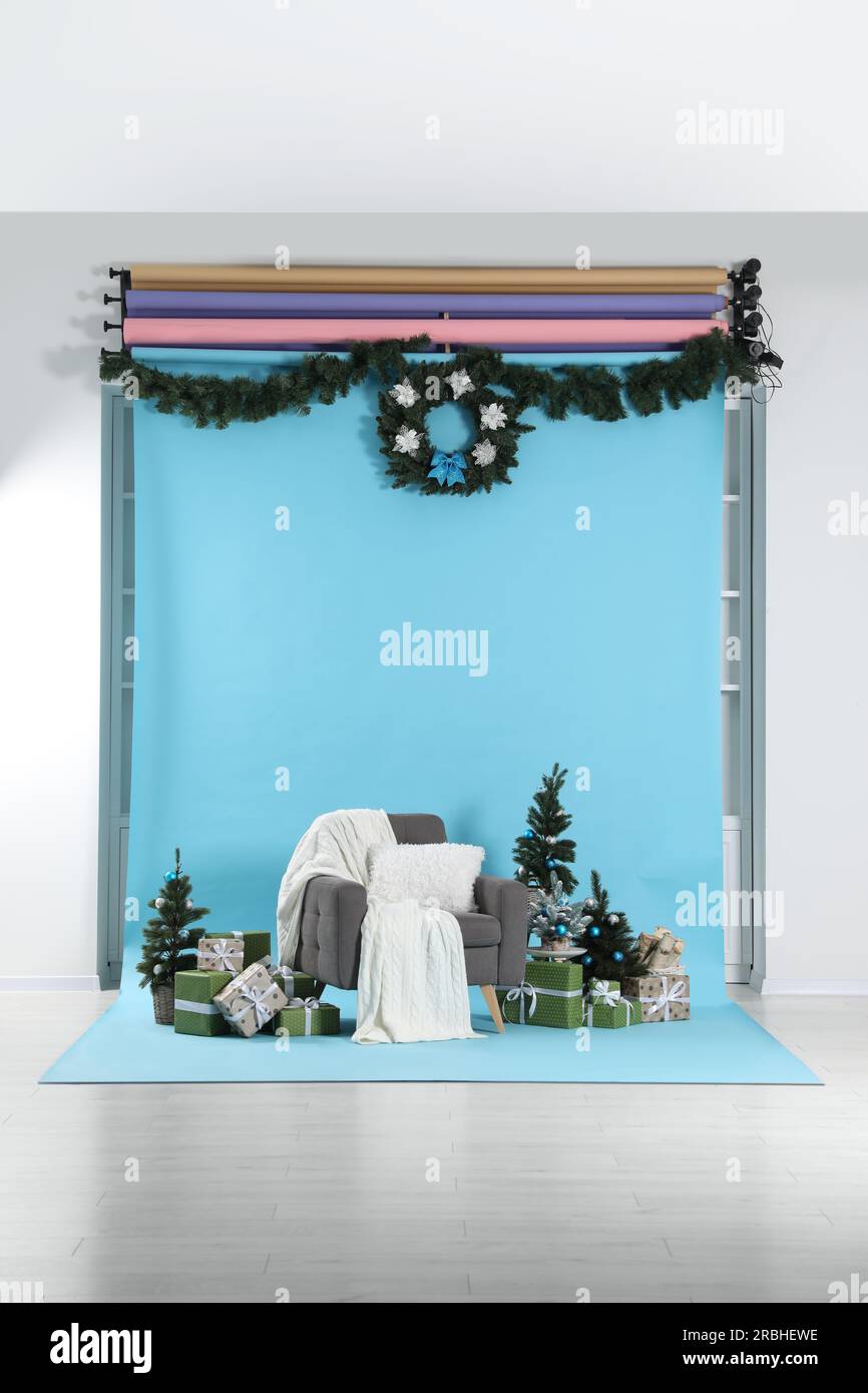 Beautiful Christmas themed photo zone with stylish armchair, trees and ...