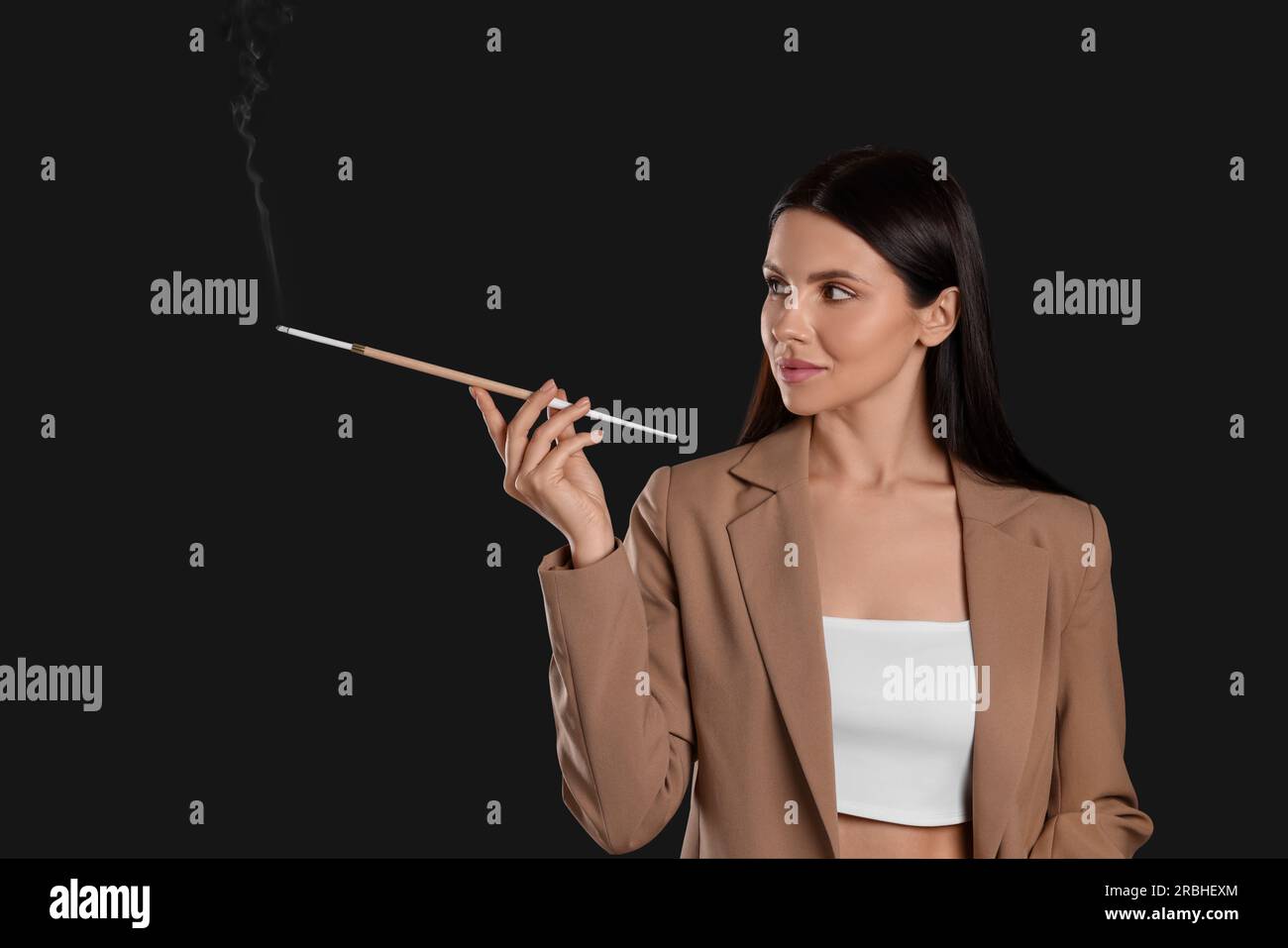 Woman using long cigarette holder for smoking on black background Stock ...