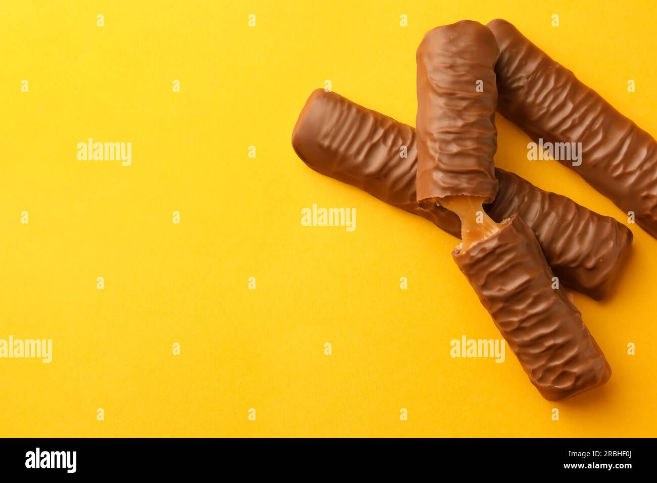 Sweet tasty chocolate bars with caramel on yellow background, flat lay ...