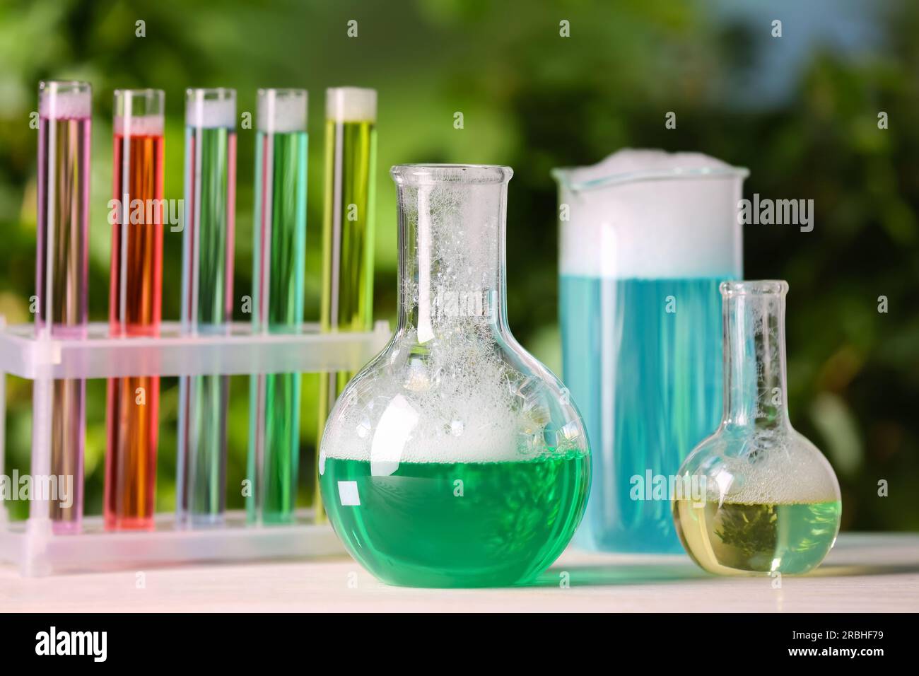 Laboratory glassware and test tubes with colorful liquids on white ...