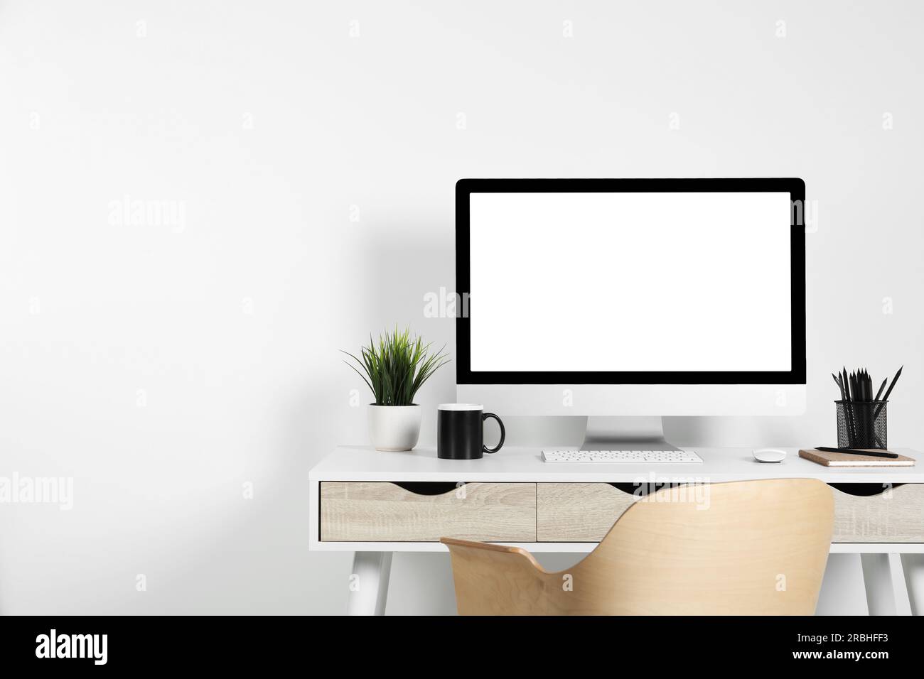 Cozy workspace with computer, houseplant and stationery on wooden desk ...