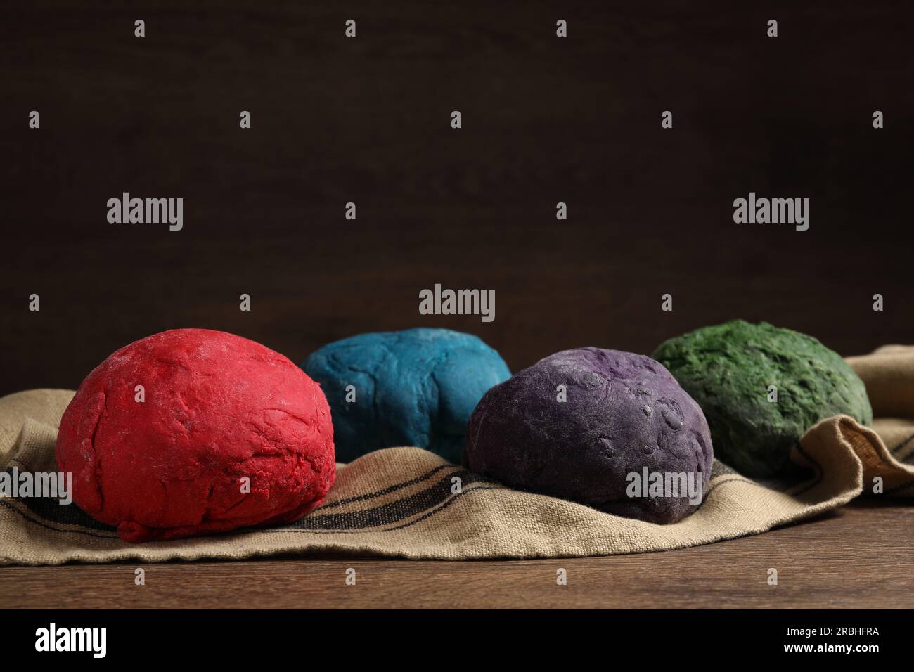 Dough painted with food colorings on wooden table, space for text Stock ...