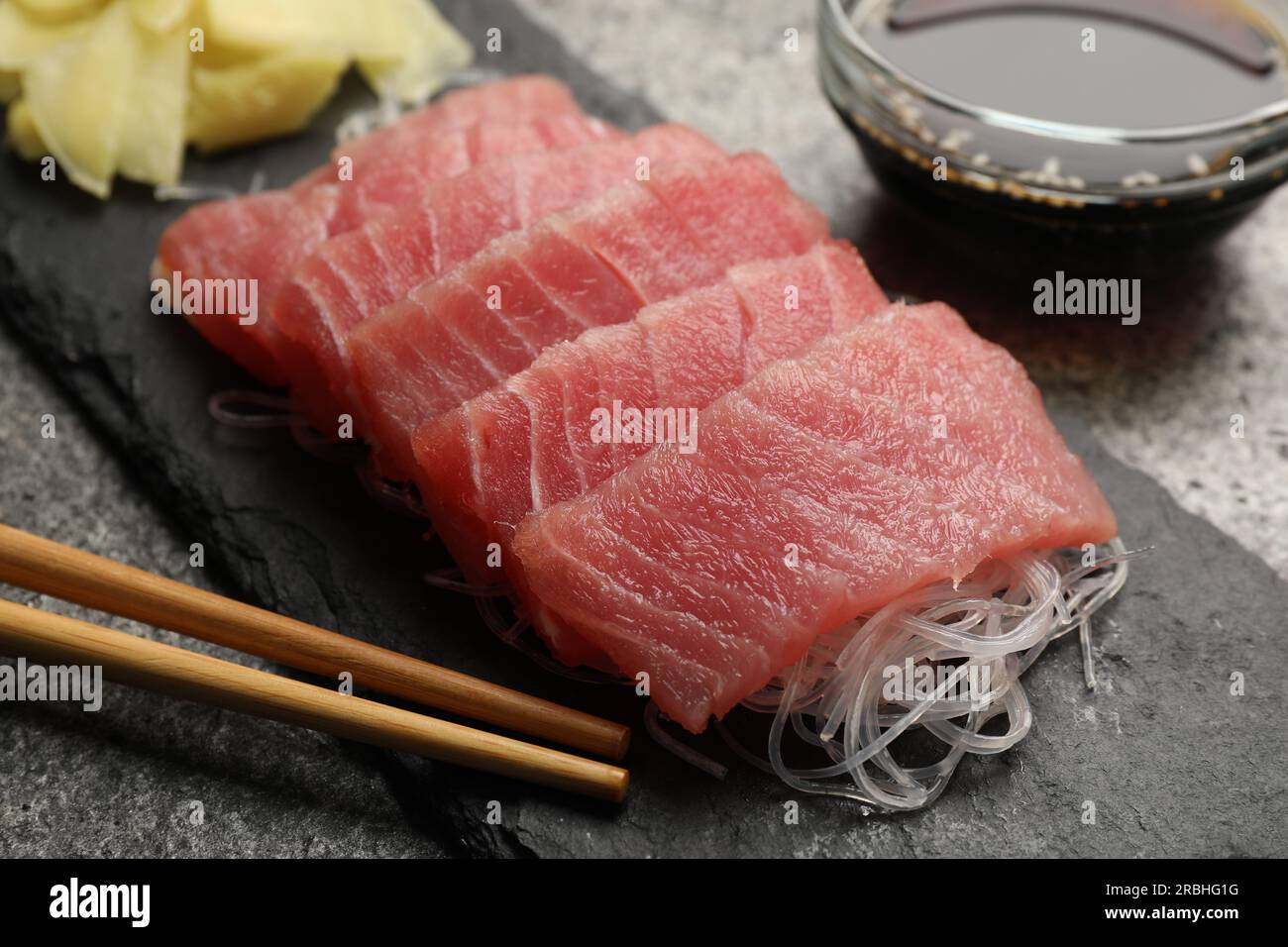 Tasty sashimi (pieces of fresh raw tuna), glass noodles and chopsticks ...
